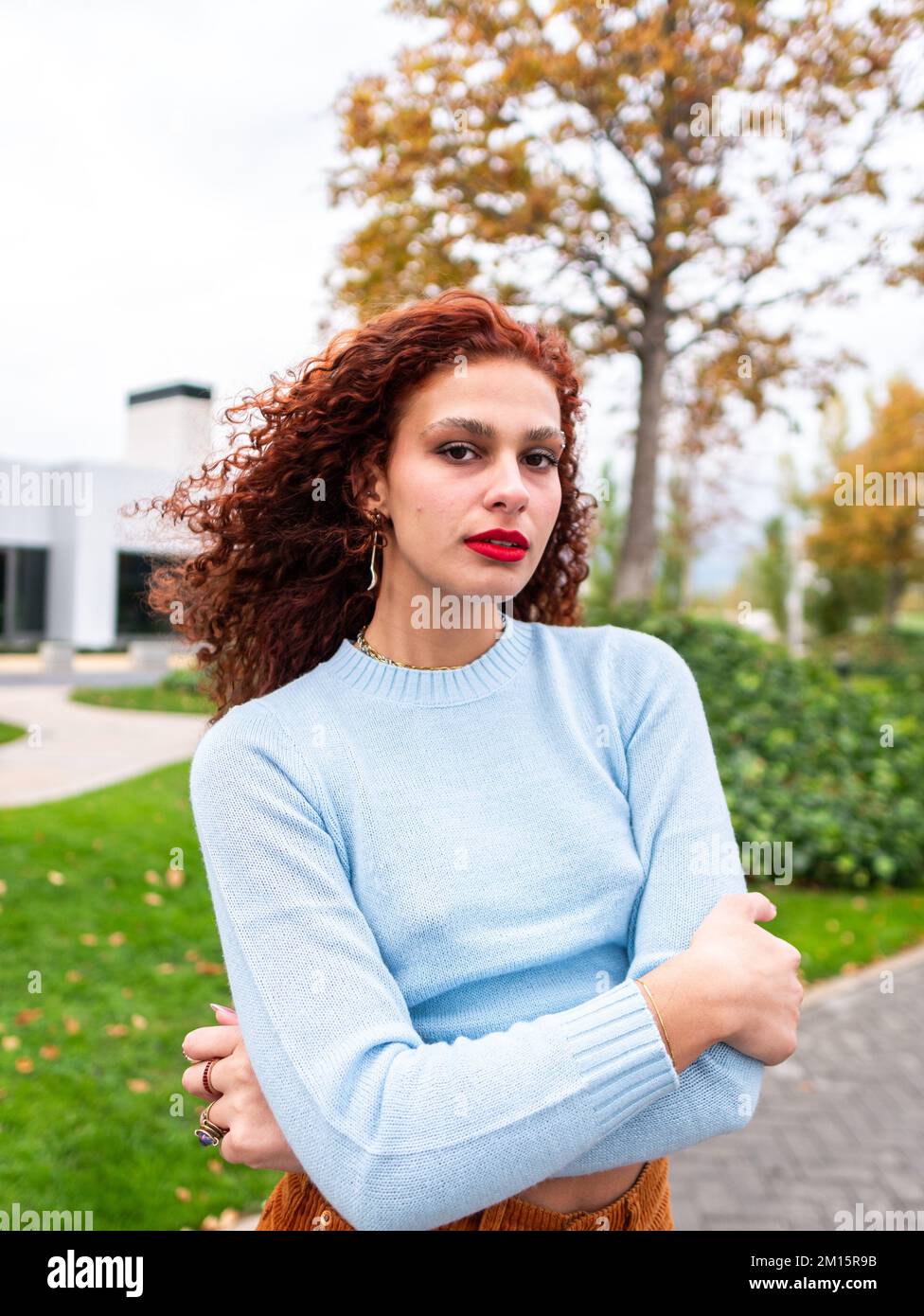 Delighted young female millennial with long curly ginger hair and red ...