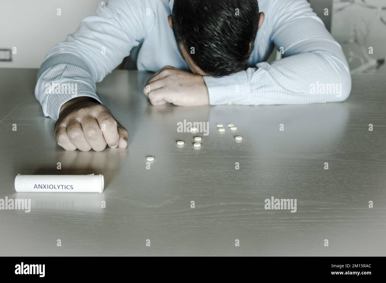 Image of a man with his head resting on the table and a tube of ...
