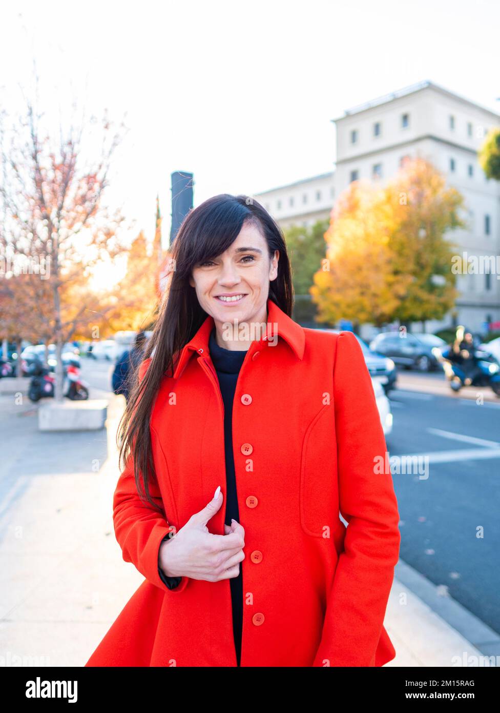 Positive adult female with long dark hair wearing bright red coat ...