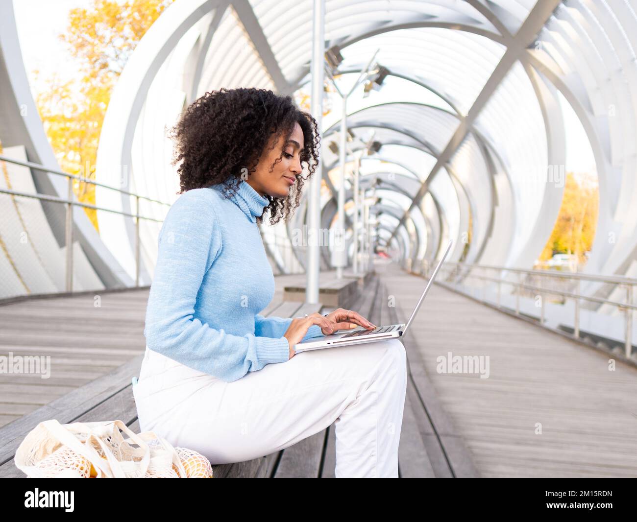 Side view of concentrated smiling ethnic female freelancer in casual ...