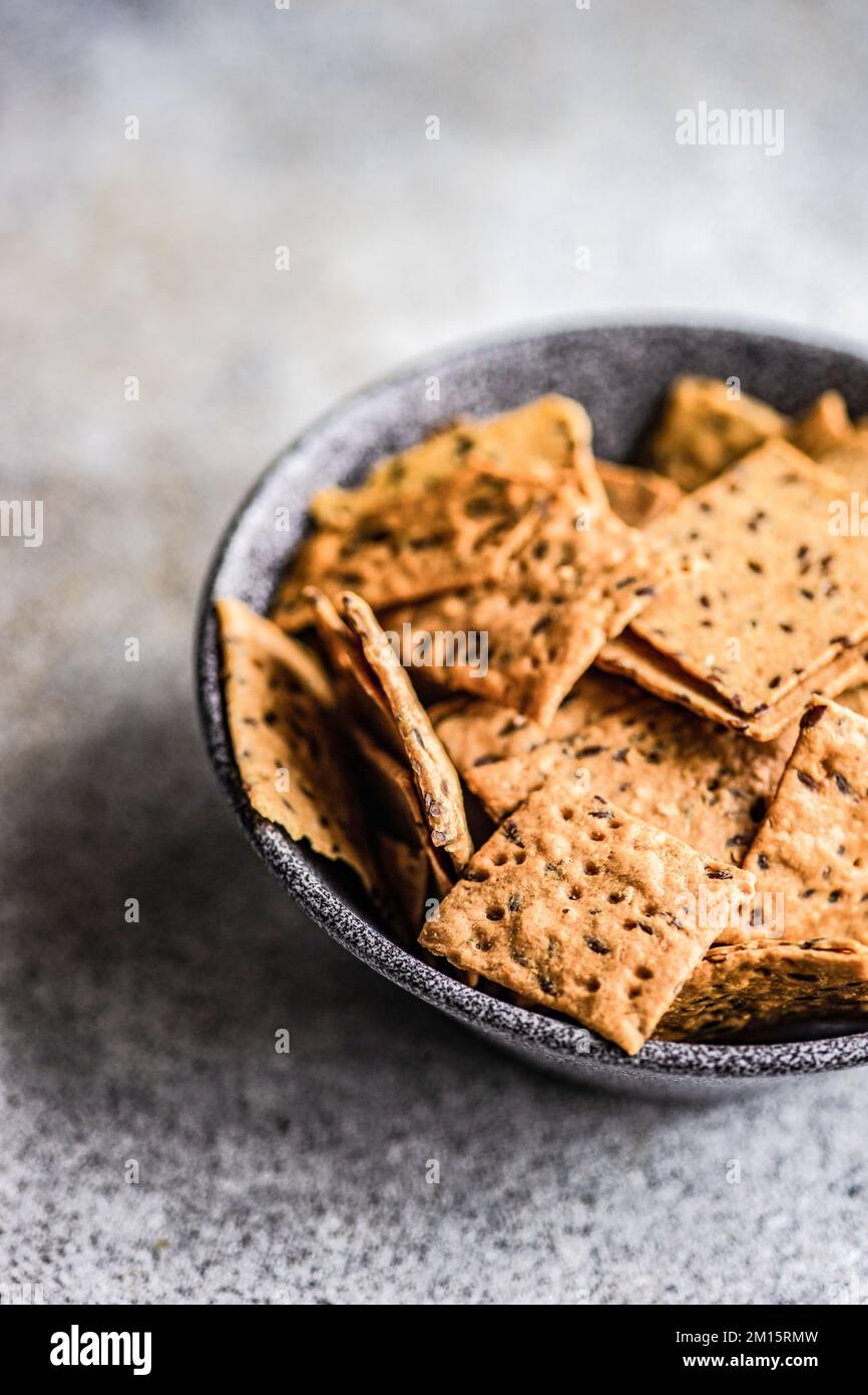Bowl of healthy flax and sesame seeds chips on the concrete background ...