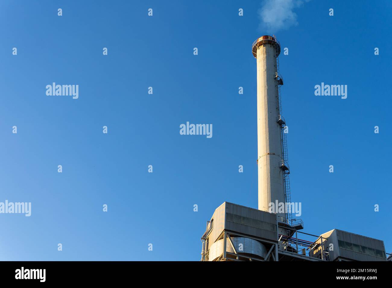 Low angle of contemporary building of industrial factory with high pipe ...