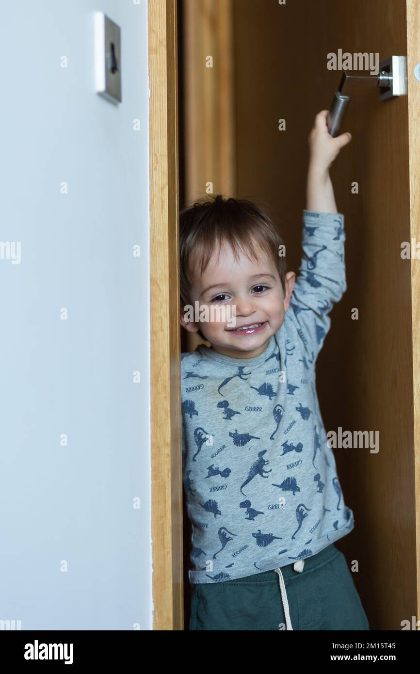 Cute toddler in pajama screaming and looking at camera while squeezing ...