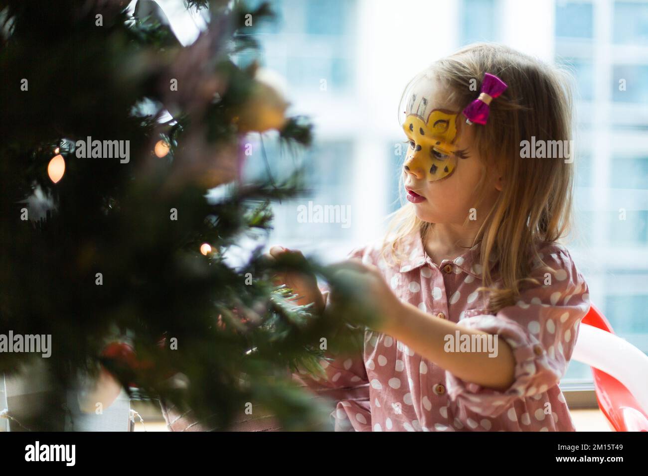 Side view of adorable girl with face painted with giraffe in pink ...
