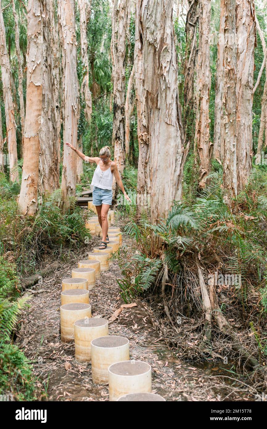 Woman in shorts and top stretching out arms and balancing on barrels ...