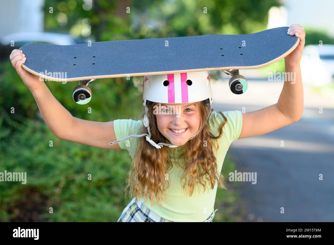 Child in protective helmet smiling and looking at camera while putting ...