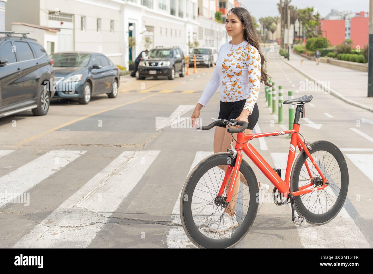 Full body female bicyclist with bike looking away and walking on ...