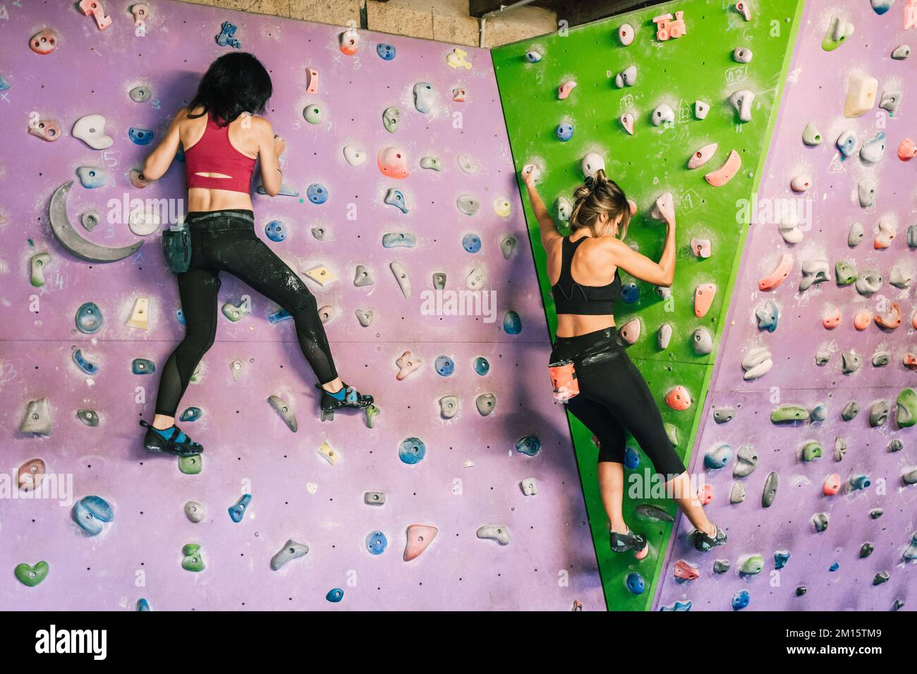 Full body female athletes climbing wall during workout in bouldering ...