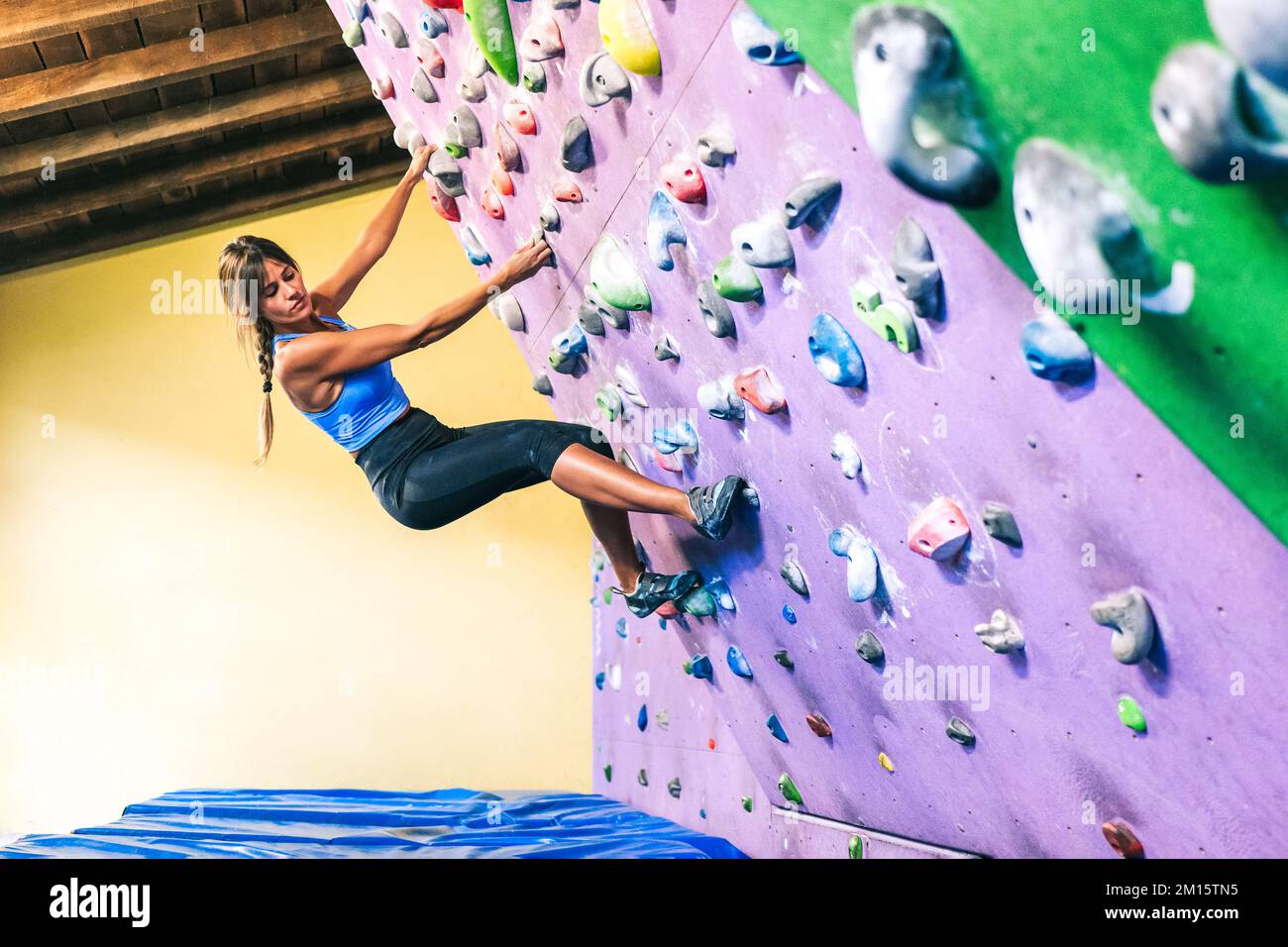 From below full body sportswoman in activewear hanging on grips of ...
