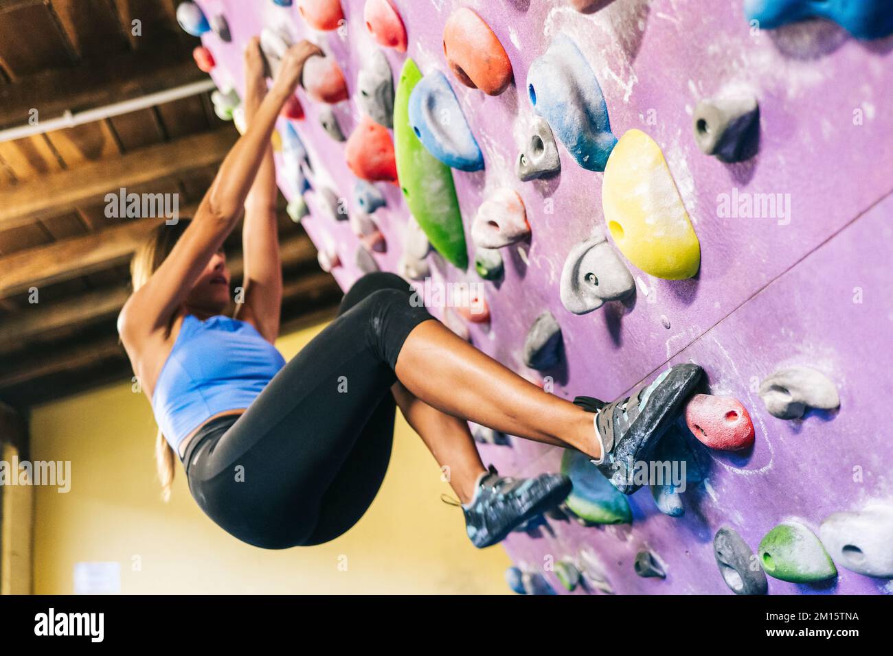 From below full body sportswoman in activewear hanging on grips of ...