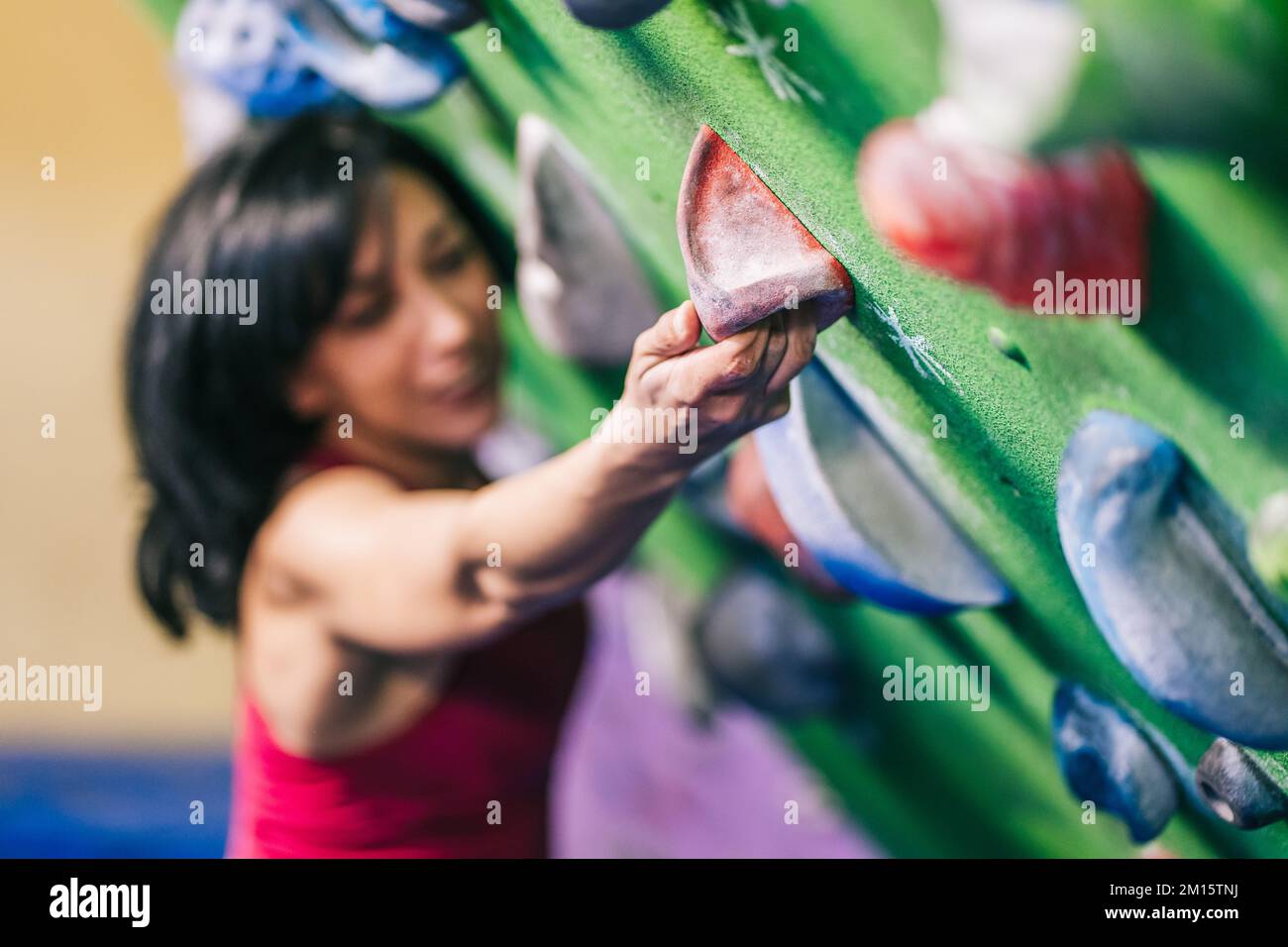 Side view of sportswoman grasping grips and tilting back while climbing ...