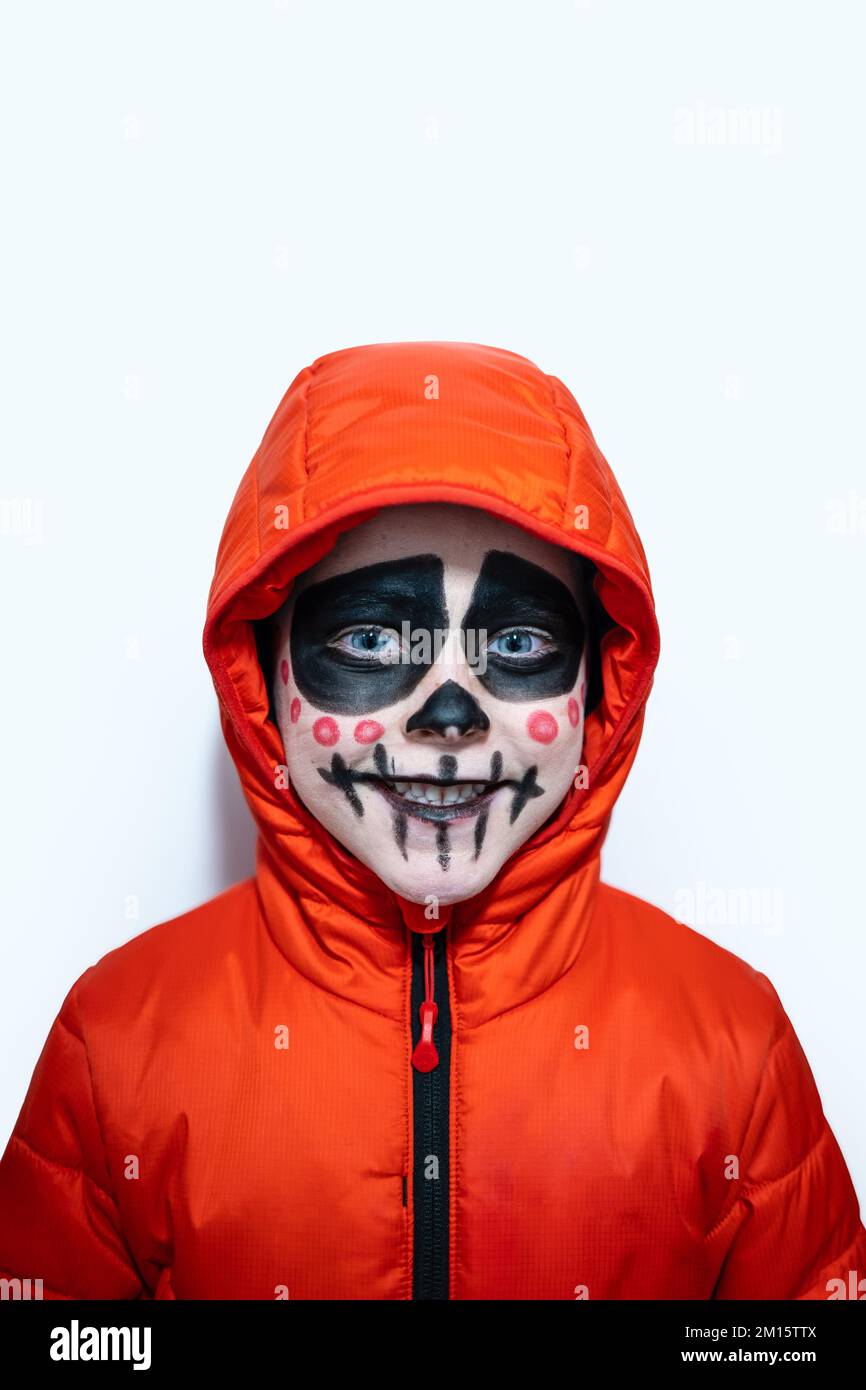 Child in orange jacket with hood and with painted face standing near ...