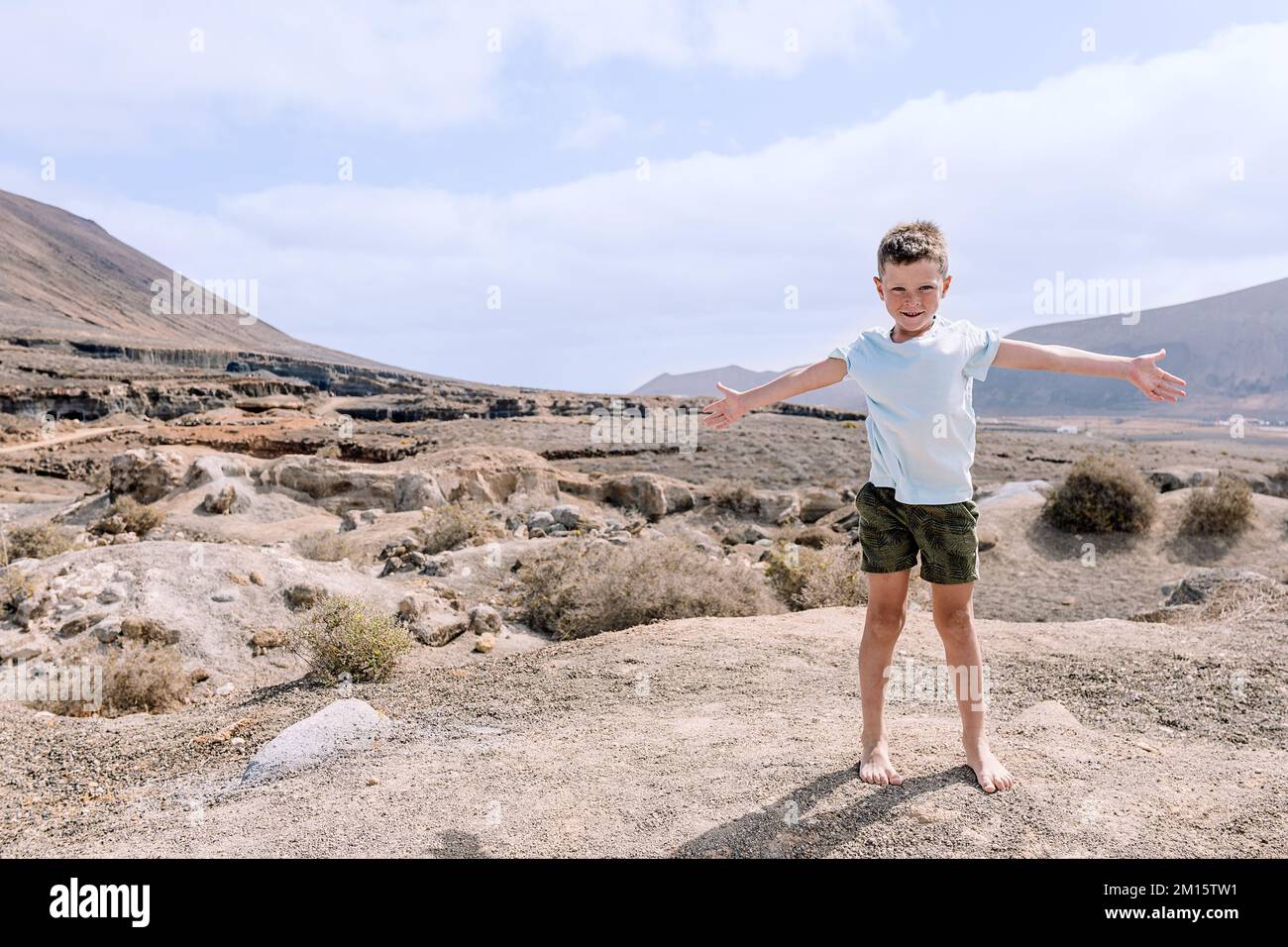 Full body of smiling preteen barefoot kid in summer clothes standing ...