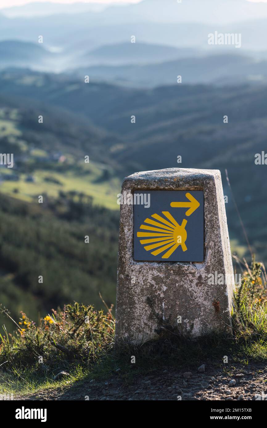 Weathered signpost with seashell symbol installed near narrow stone ...