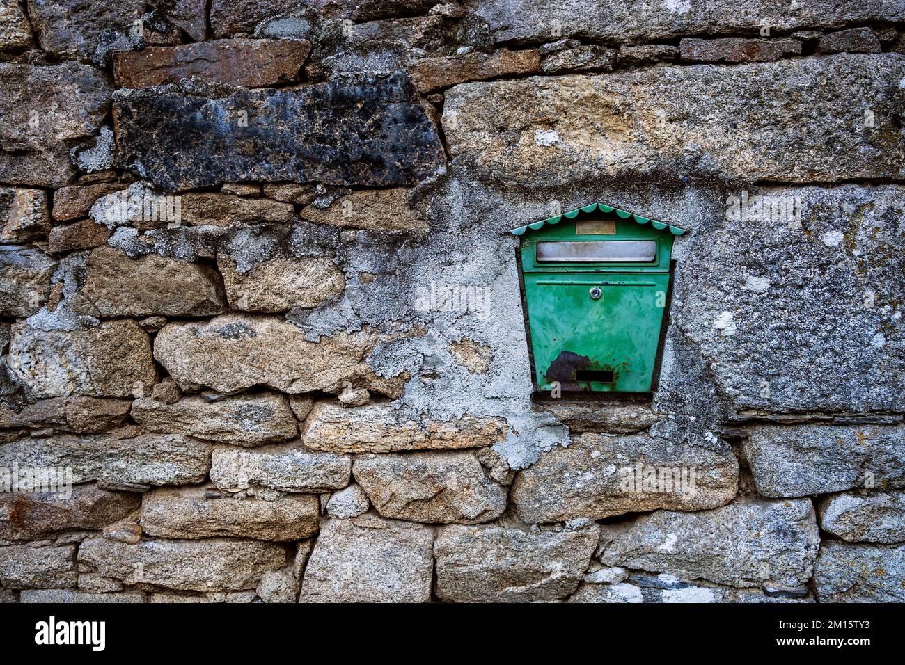 Green colored metal vintage mail box in wall made of rough aged stones ...
