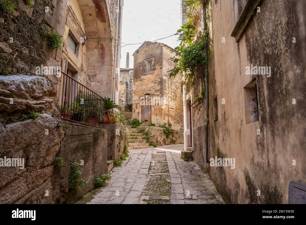 Narrow path going through ancient stone buildings with shabby walls and ...