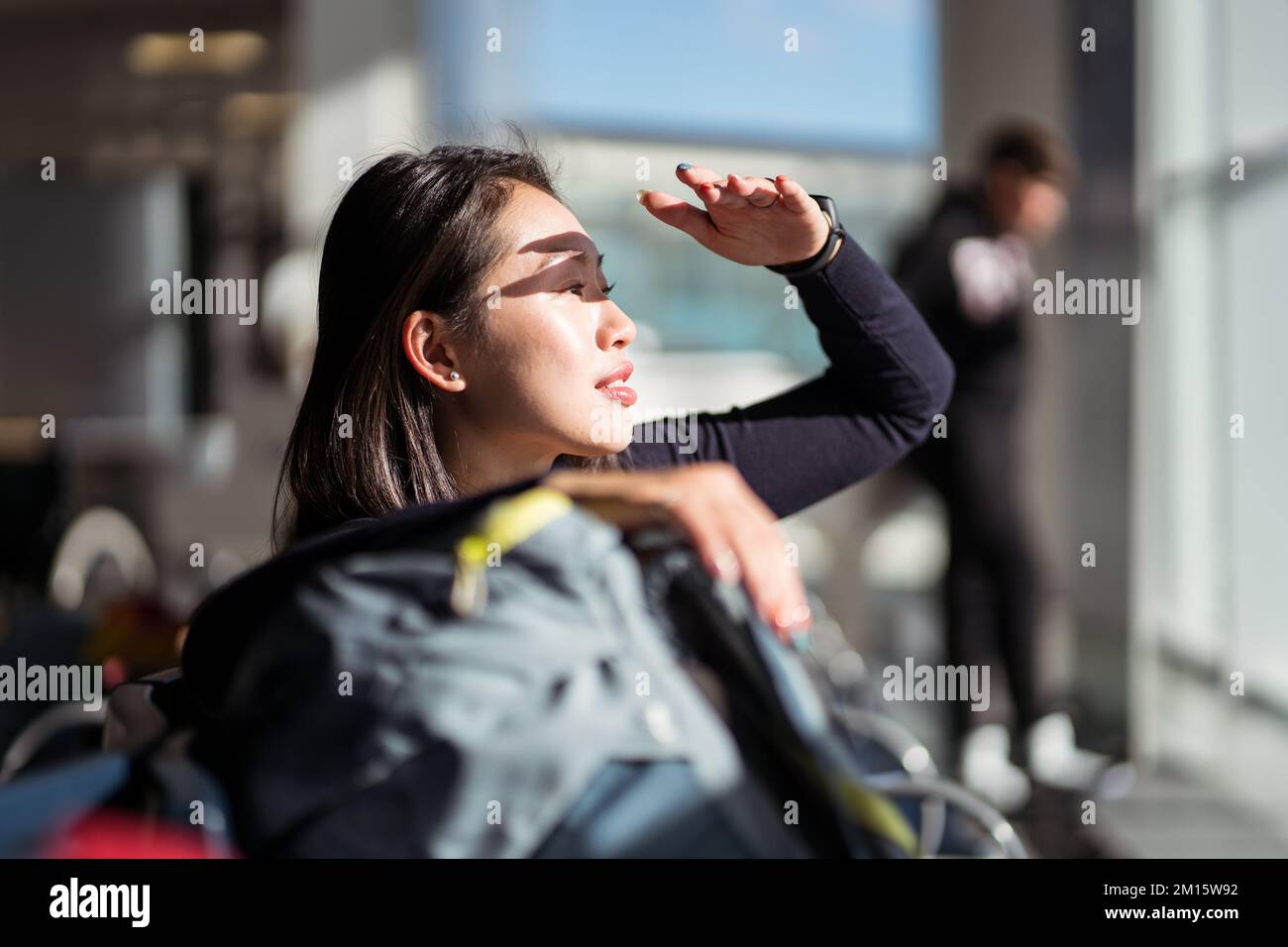 Young Asian female tourist protecting eyes from sunlight and looking ...