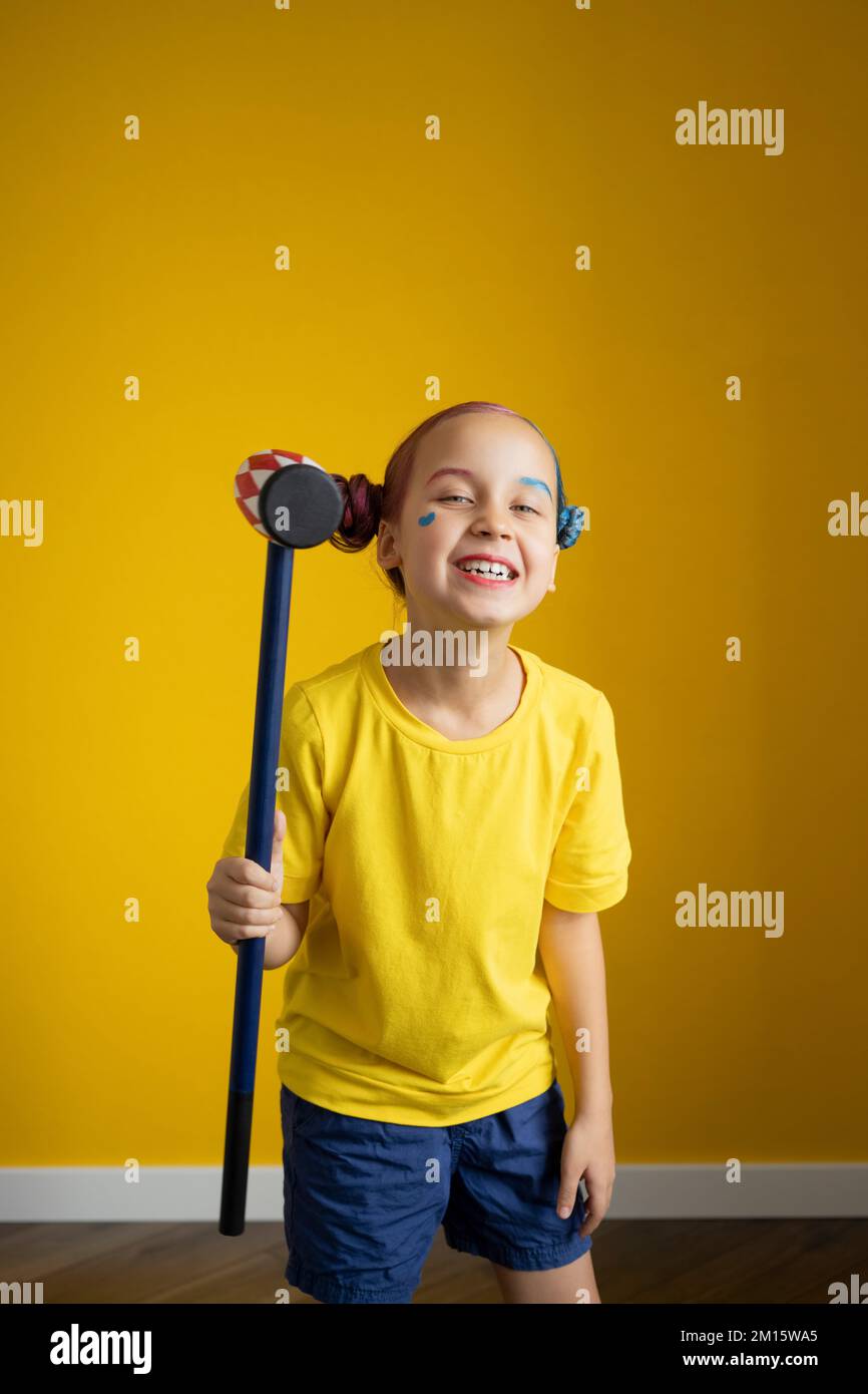 Cute smiling kid with blue and pink hair buns standing with mallet ...
