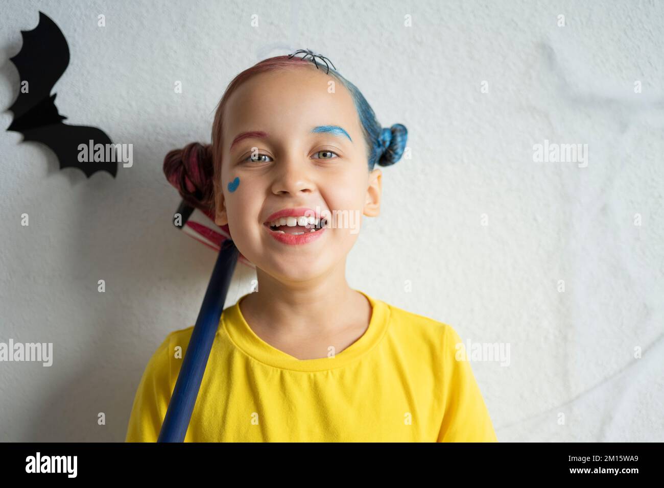 Cute smiling kid with blue and pink hair buns standing with mallet ...