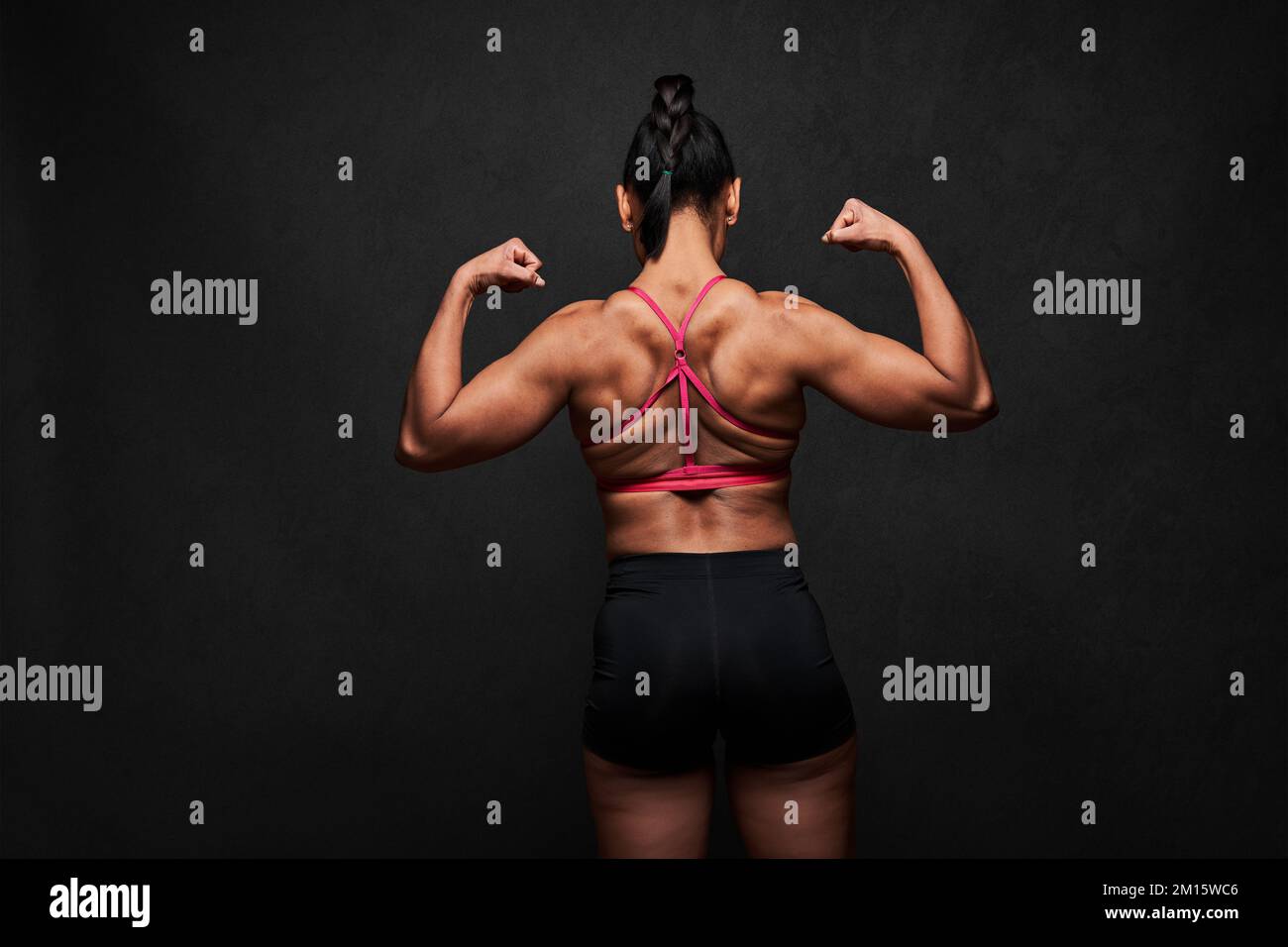Back view of unrecognizable strong female athlete in red top standing ...