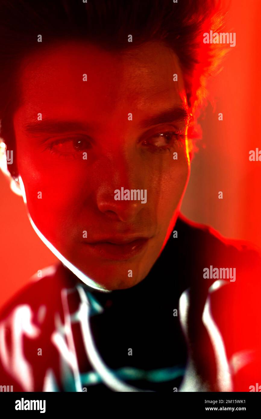 Male model standing in dark studio with glowing red neon lights and ...