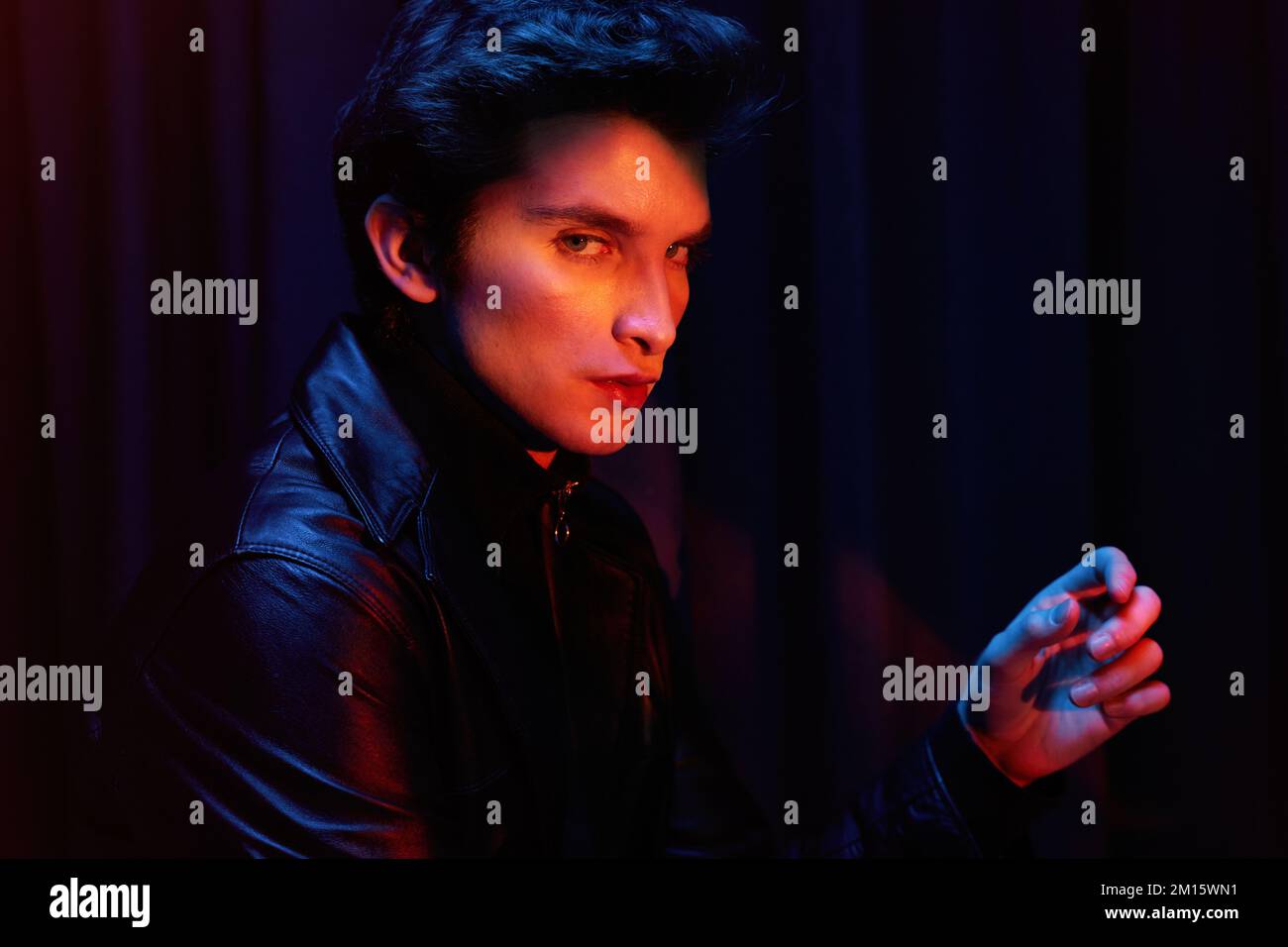 Male model standing in dark studio with glowing red neon lights and ...