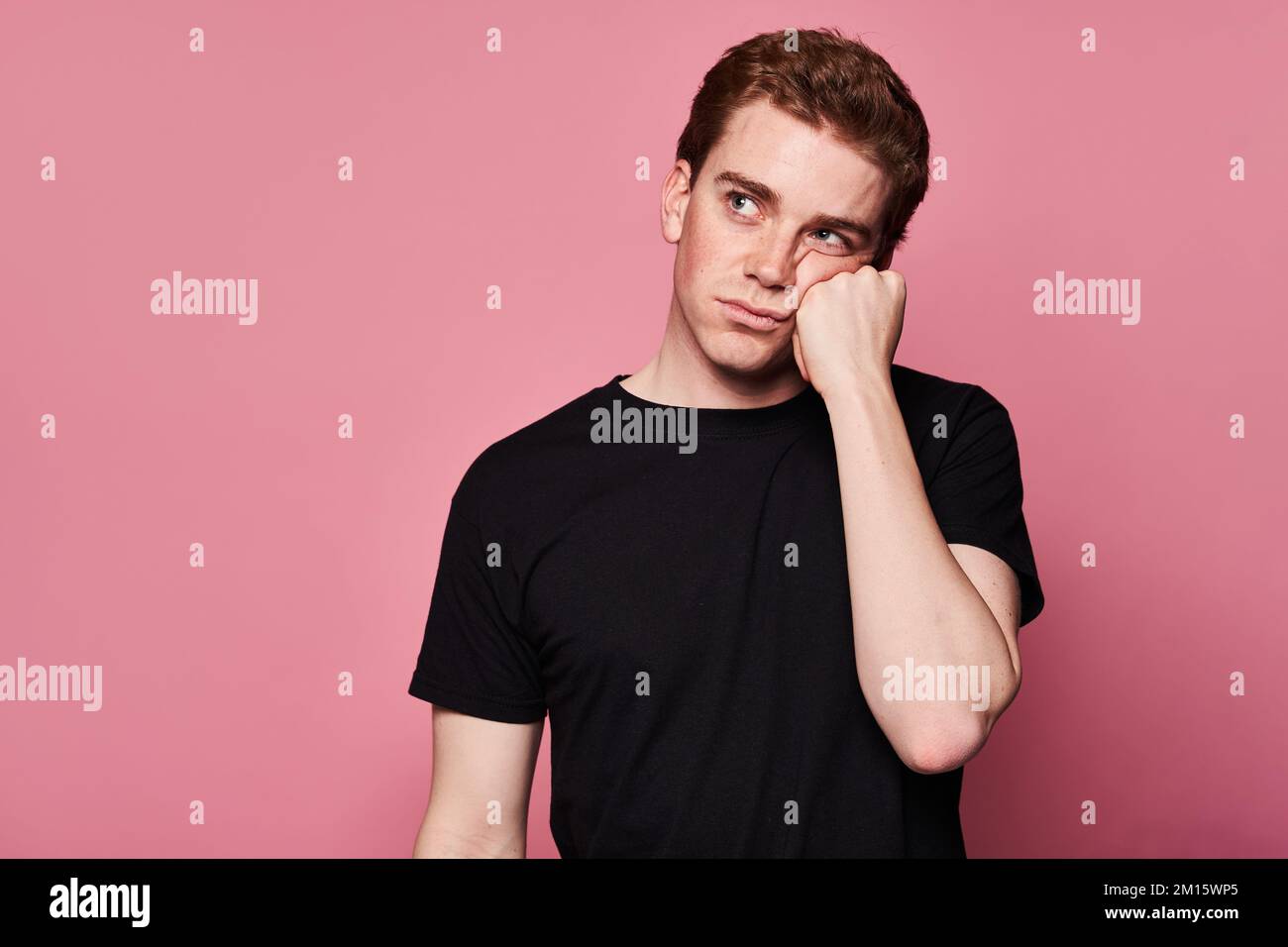Indifferent young man in black t shirt with ginger hair looking away ...