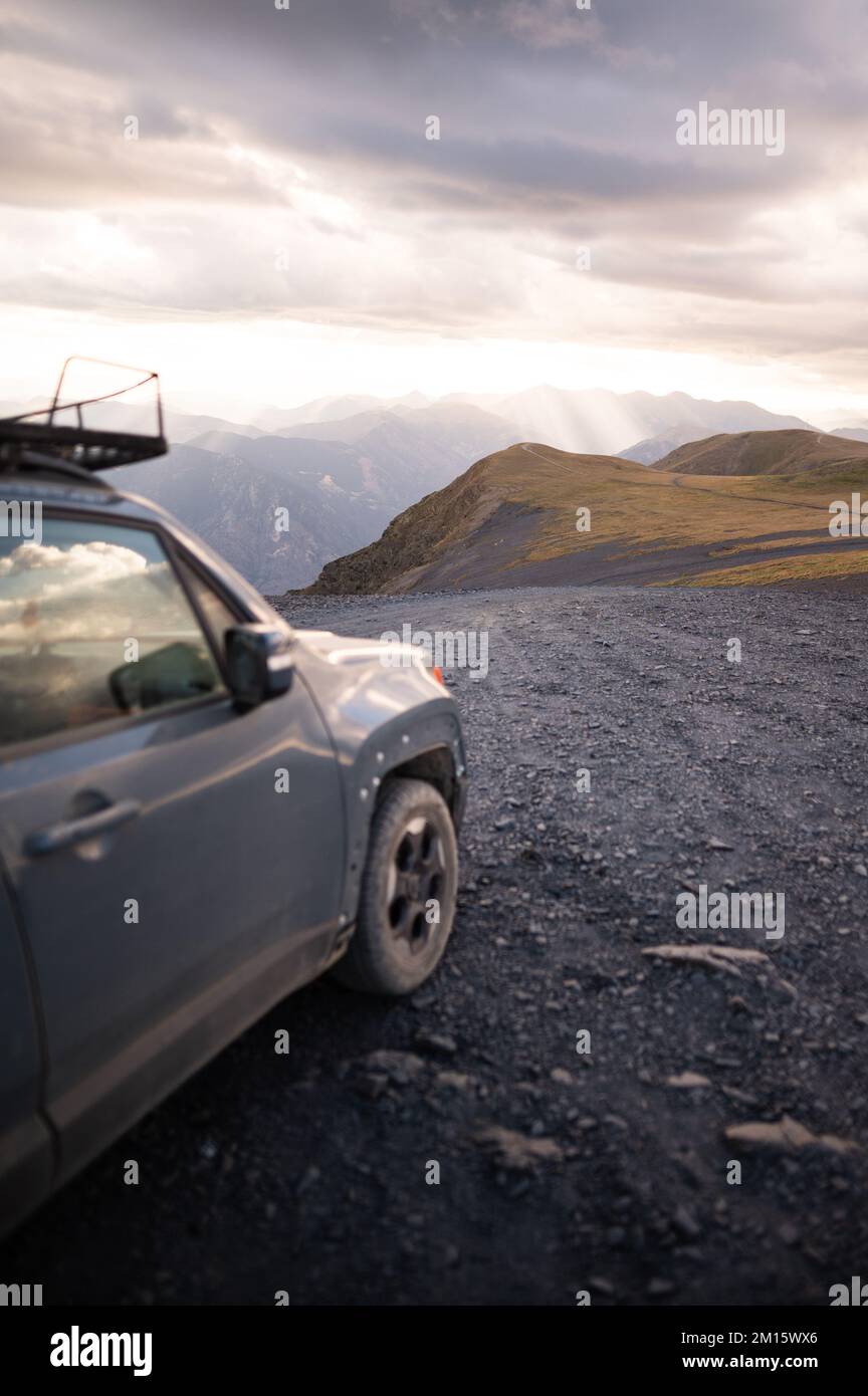 Modern gray automobile parked on road near mountain ridge on cloudy ...