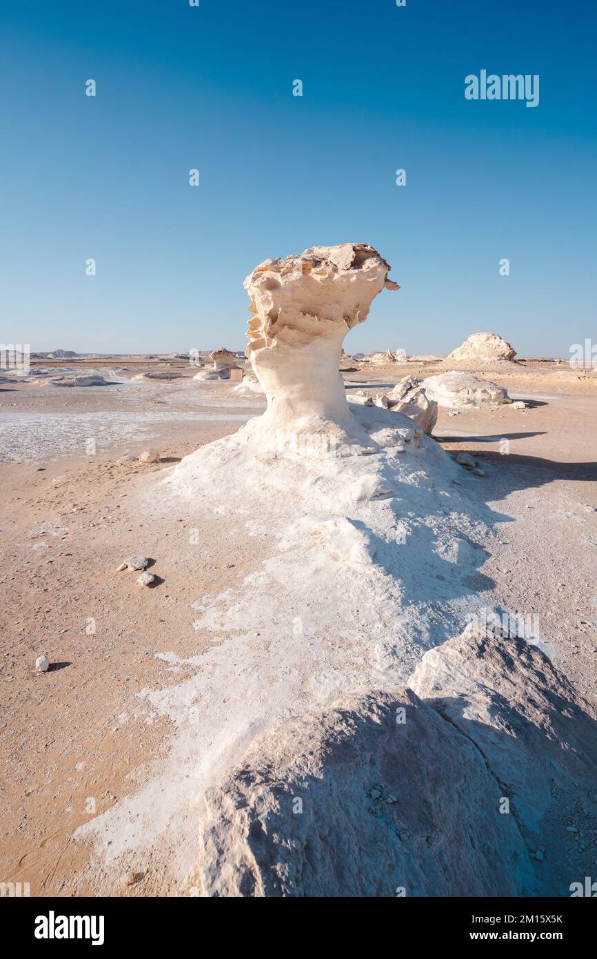 White formations located in sandy desert terrain under blue cloudless ...