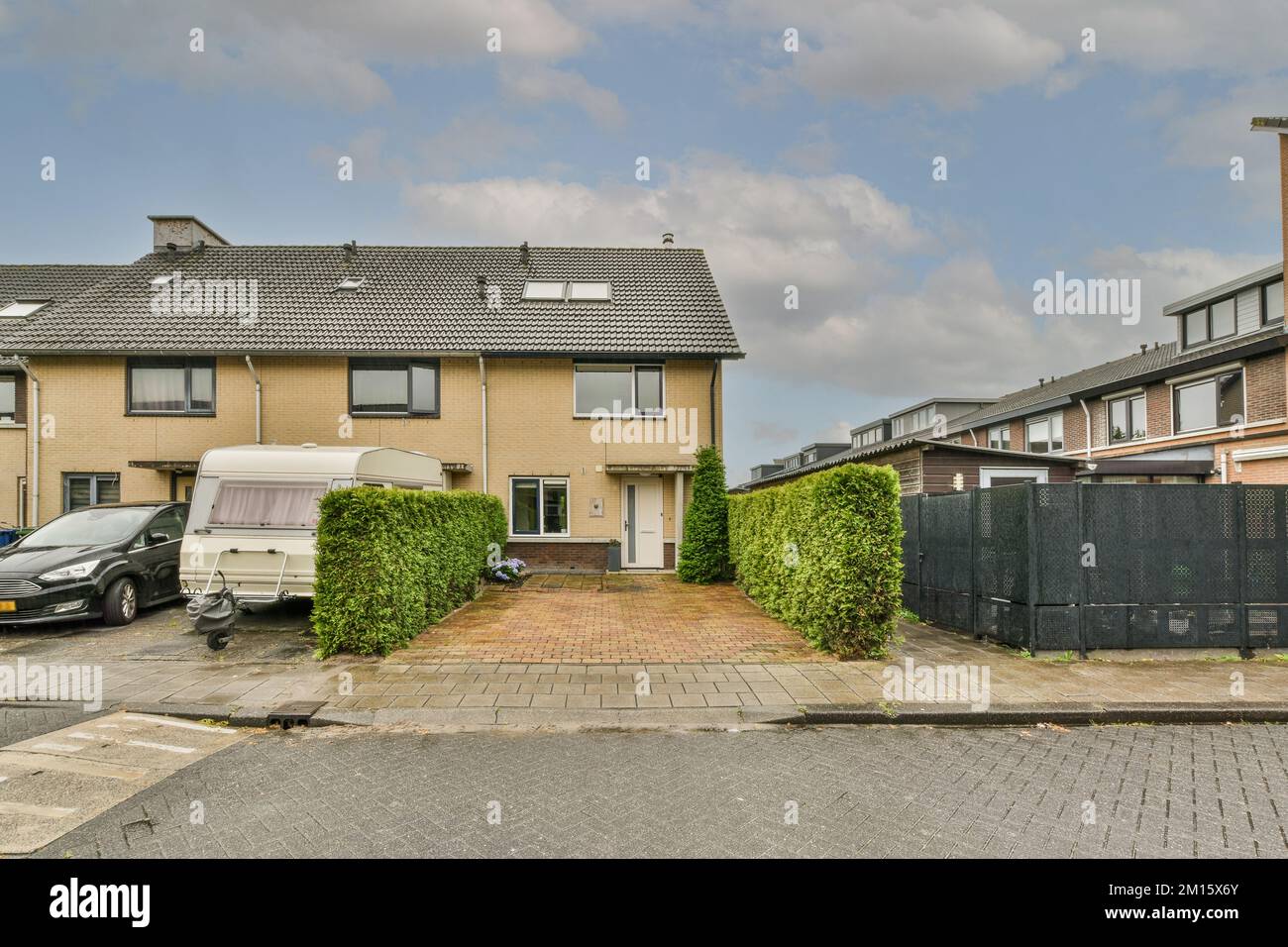 View of a street with houses lined up under a blue sky with clouds ...