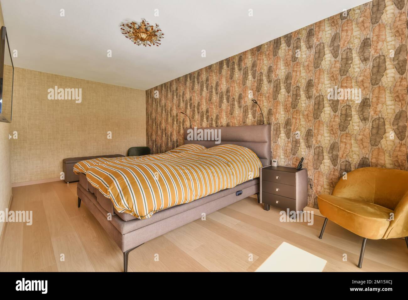 Comfortable bed next to a chair and wooden floor Stock Photo - Alamy