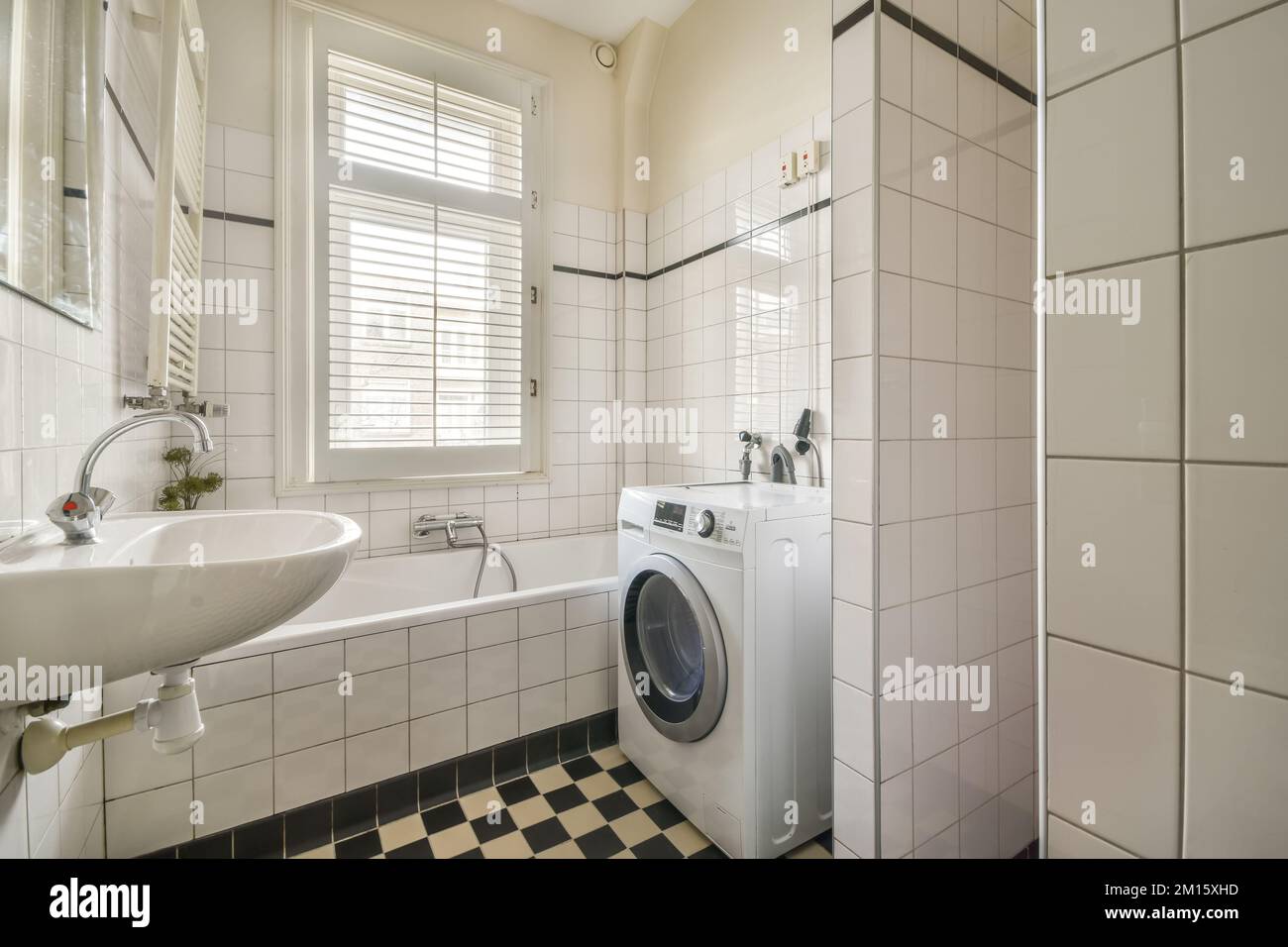 Interior of modern white tiled bathroom with washing machine bathtub ...