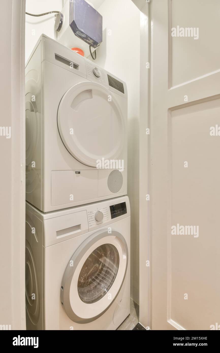 Modern washing and dryer machines placed in light bathroom with white ...
