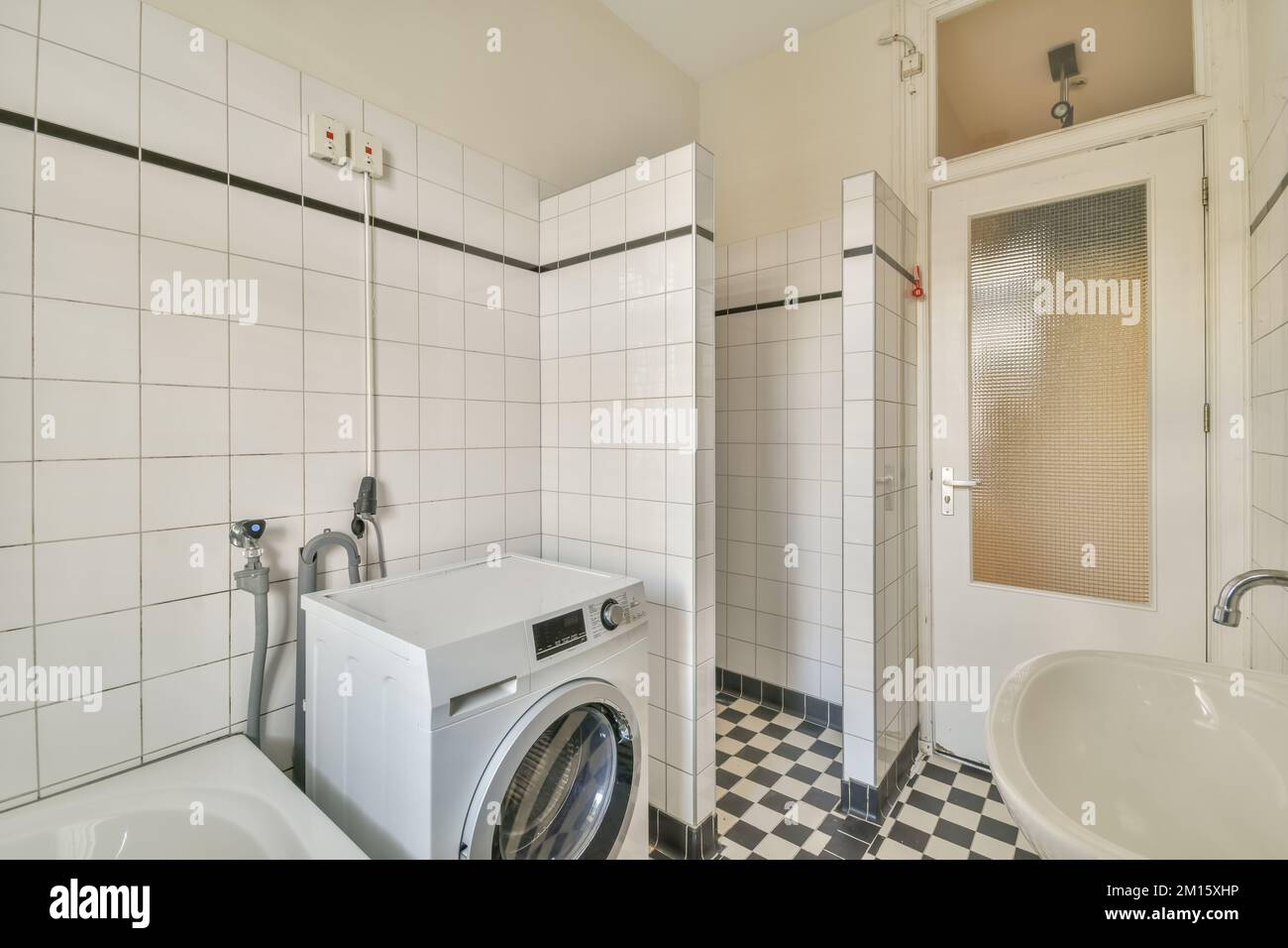 Interior of modern white tiled bathroom with washing machine bathtub ...