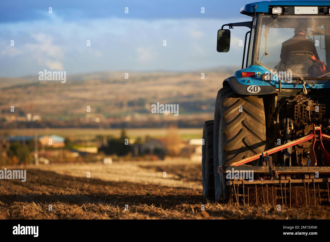 Back view of unrecognizable farmer driving tractor while working soil ...