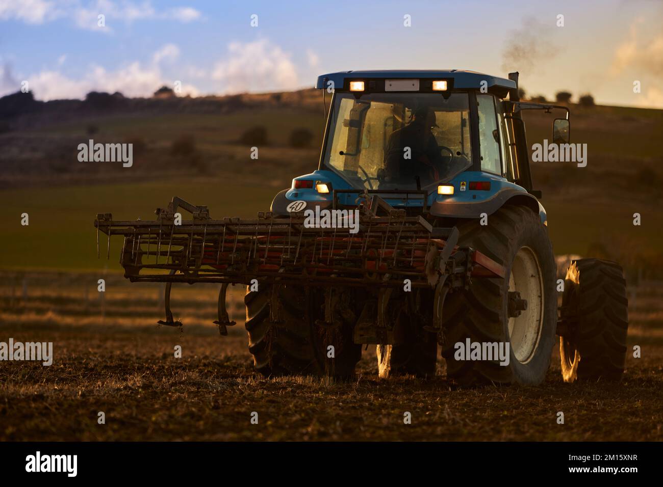 Back view of unrecognizable farmer driving tractor while working soil ...