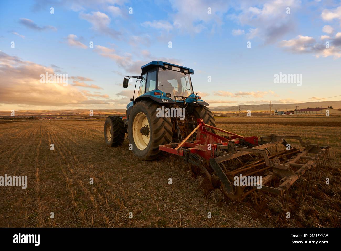 Back view of unrecognizable farmer driving tractor while working soil ...