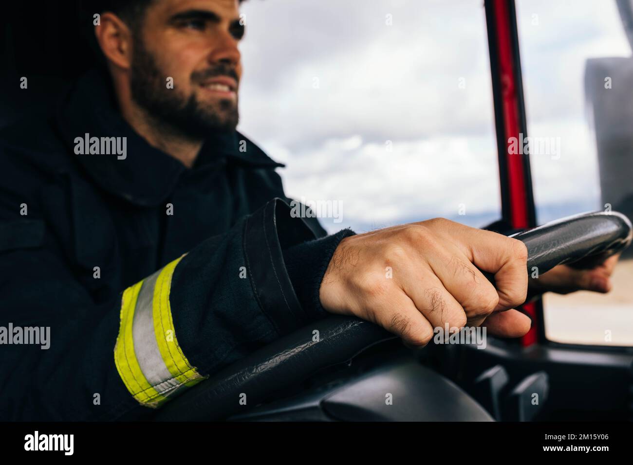 Side view of Hispanic focused firefighter in protective uniform smiling ...