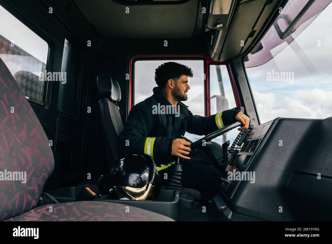 Side view of Hispanic focused firefighter in protective uniform smiling ...