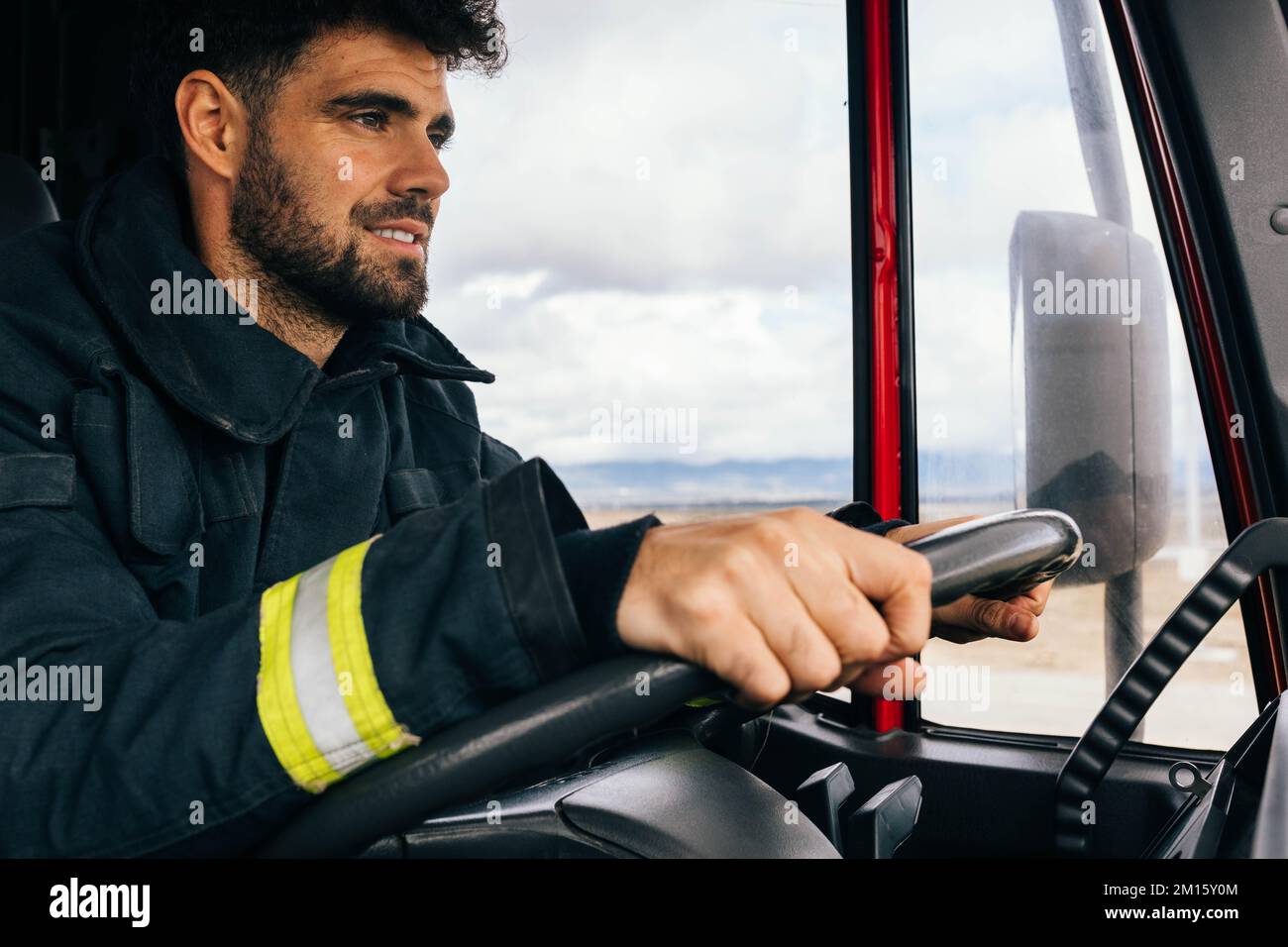 Side view of Hispanic focused firefighter in protective uniform smiling ...