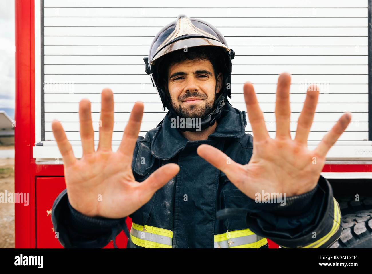 Hispanic fireman in uniform and helmet demonstrating hands covered with ...