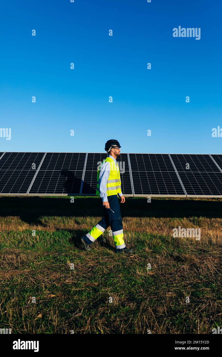 Bearded worker in protective helmet with screwdriver walking while ...