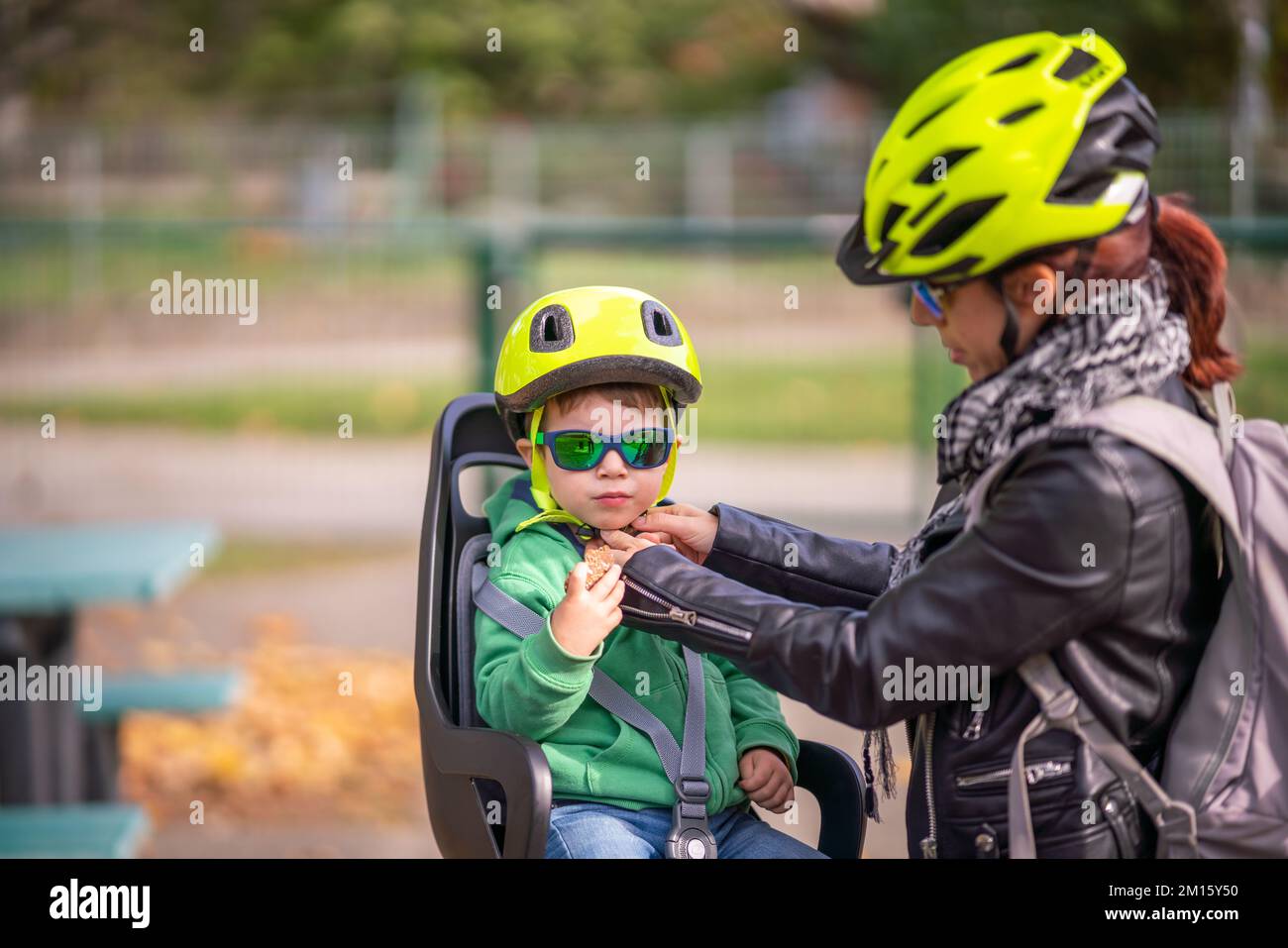 Young woman in leather jacket with backpack clasping boys yellow helmet ...