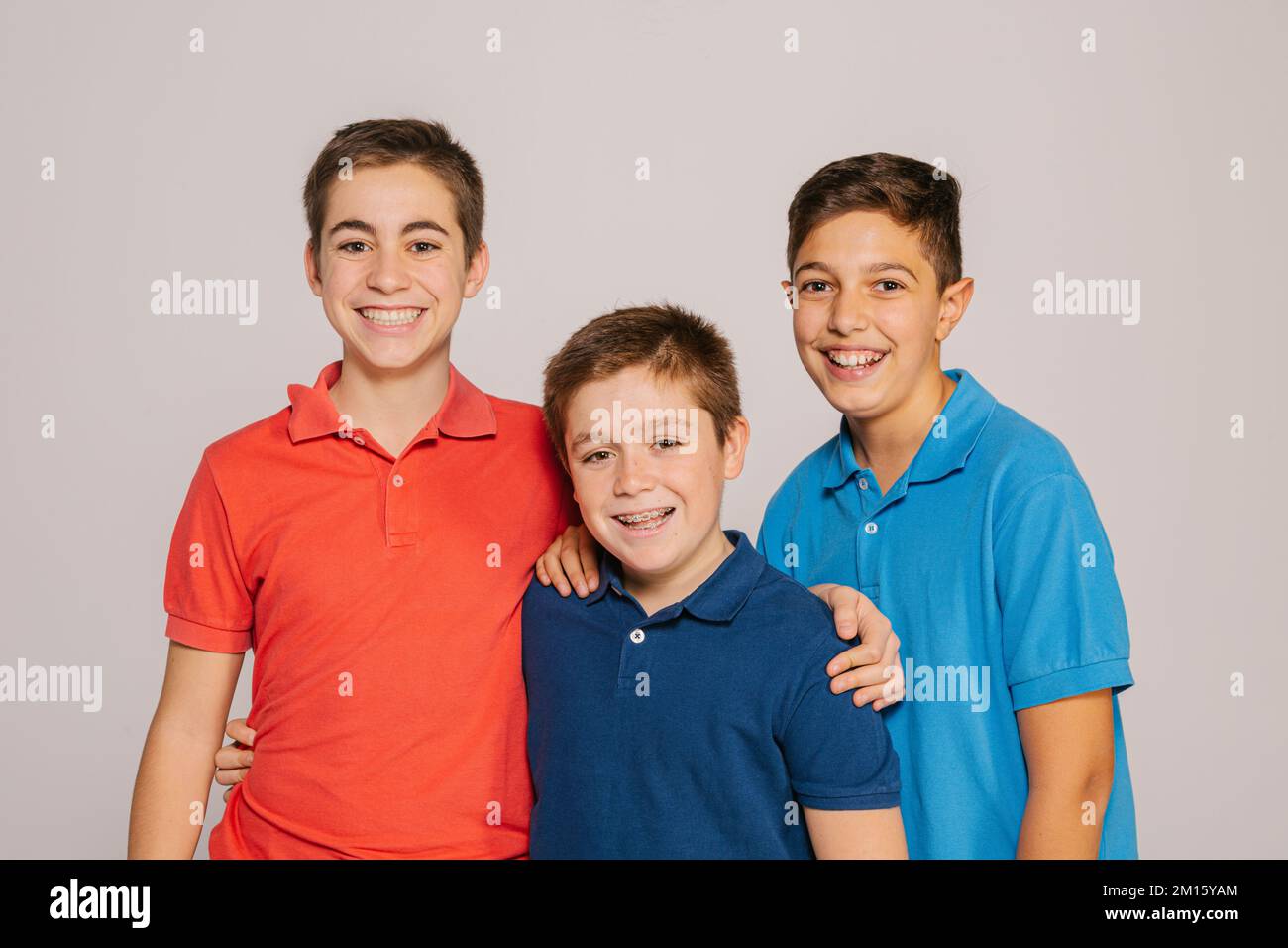 Happy young kids smiling and looking at camera while standing against ...