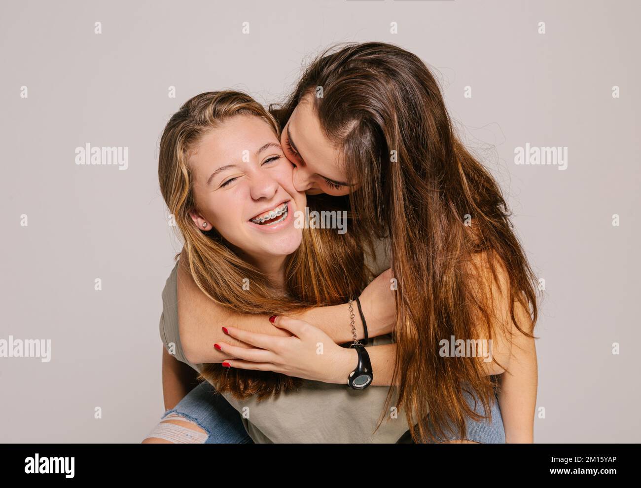 Positive young girl with long hair hugging her best friend and looking ...