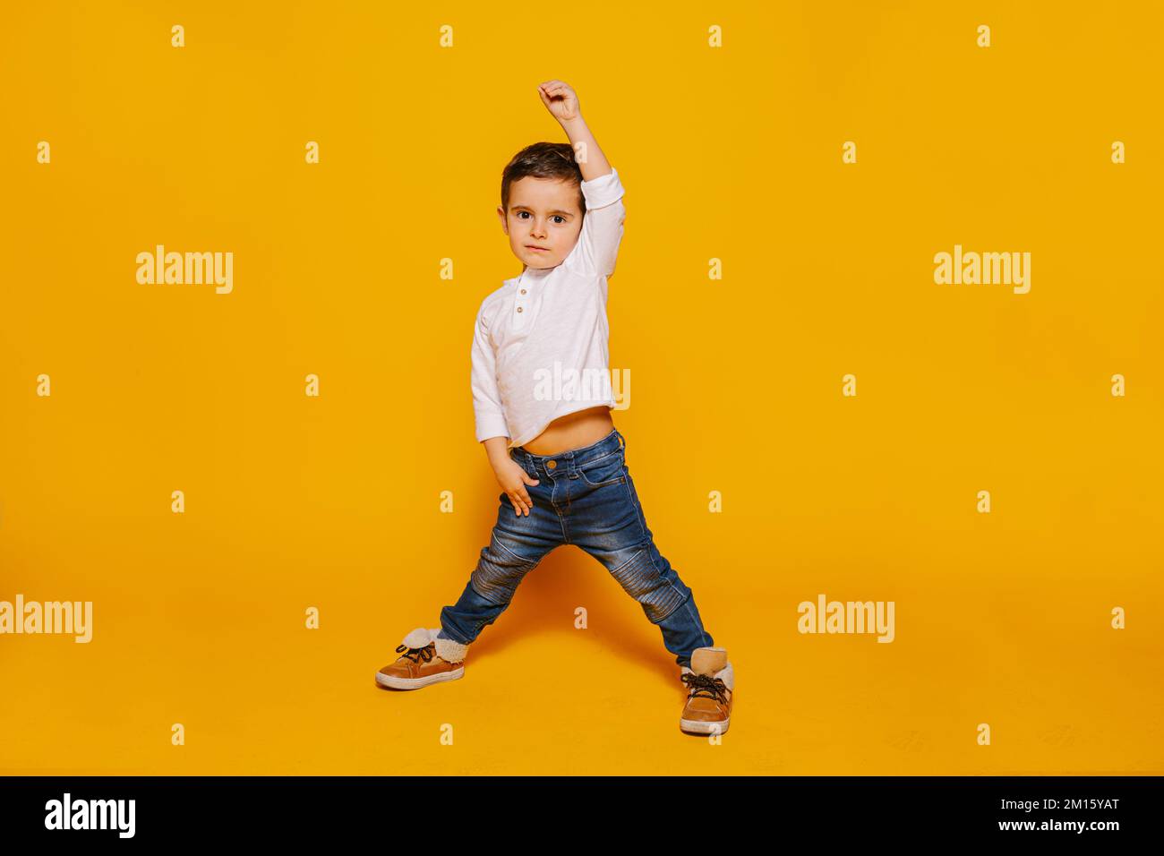 Full body of cute little kid in casual outfit smiling and looking at ...