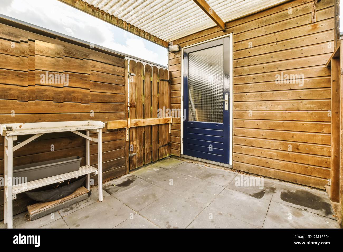 an outside area with wood siding on the walls, and a blue door in the ...