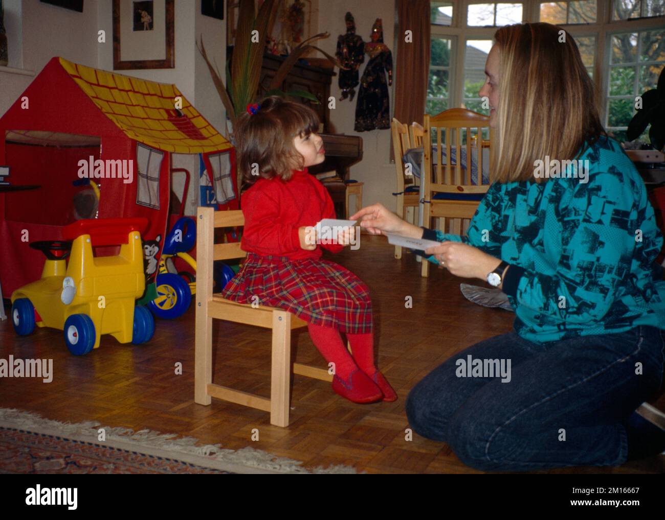 Two Year Old Girl Sitting in Chair while Au Pair Shows her Flash Cards ...
