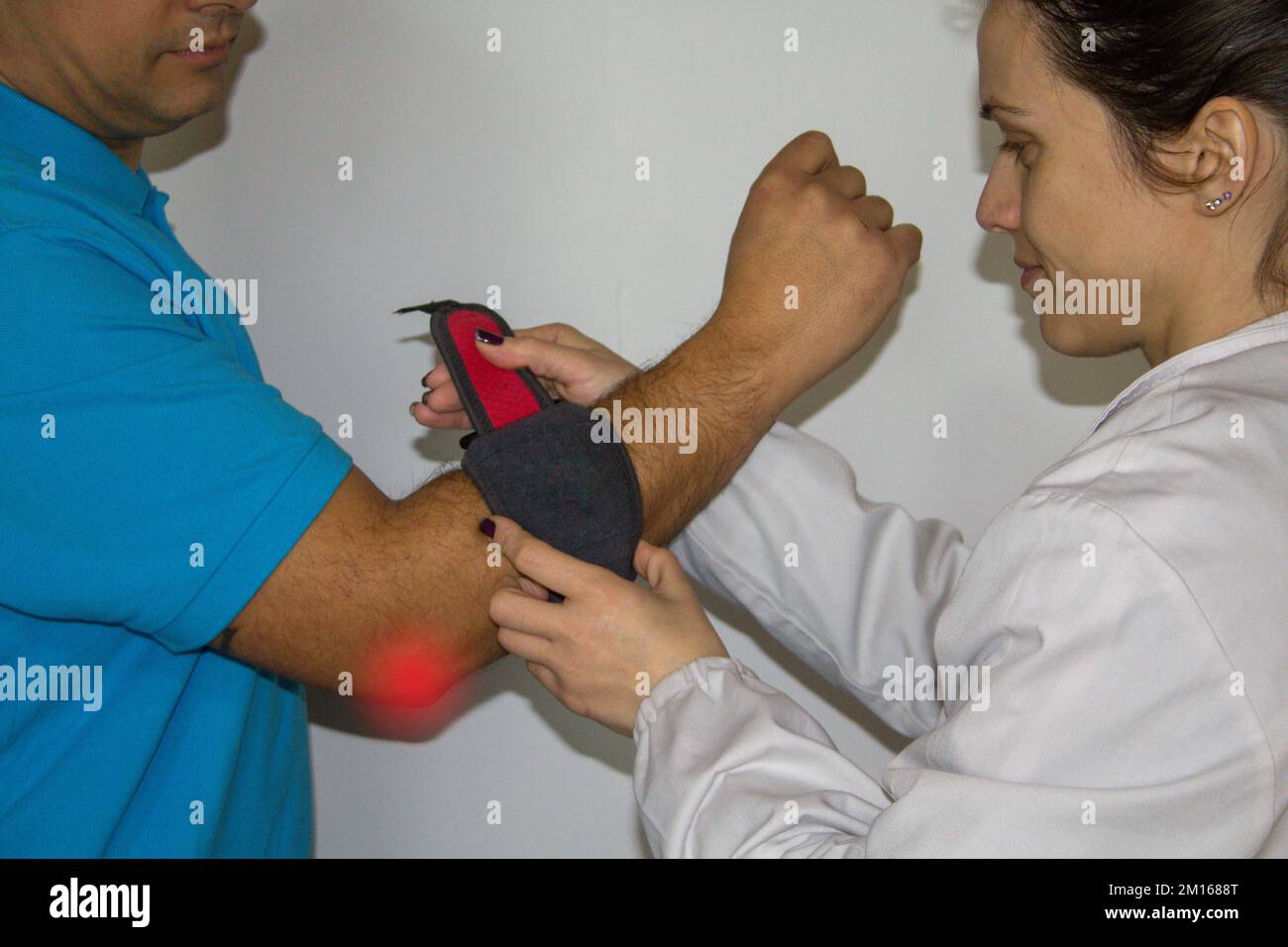 Image of a female physiotherapist showing a patient with epicondylitis ...