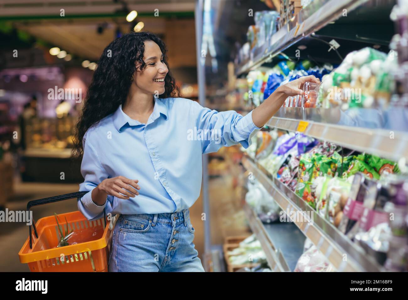 A young beautiful Hispanic woman buys cherry tomatoes in a supermarket ...